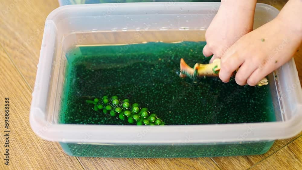Little girl playing in handmade swamp of green-dyed chia seeds with ...