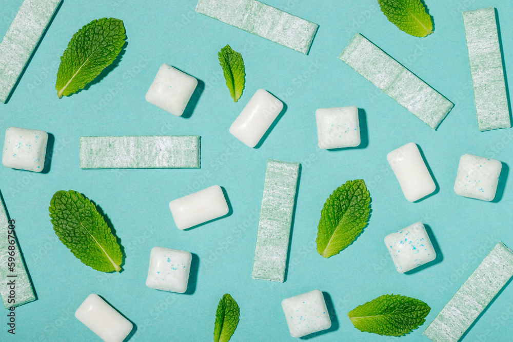 Different types of mint chewing gum and fresh mint leaves on a blue ...