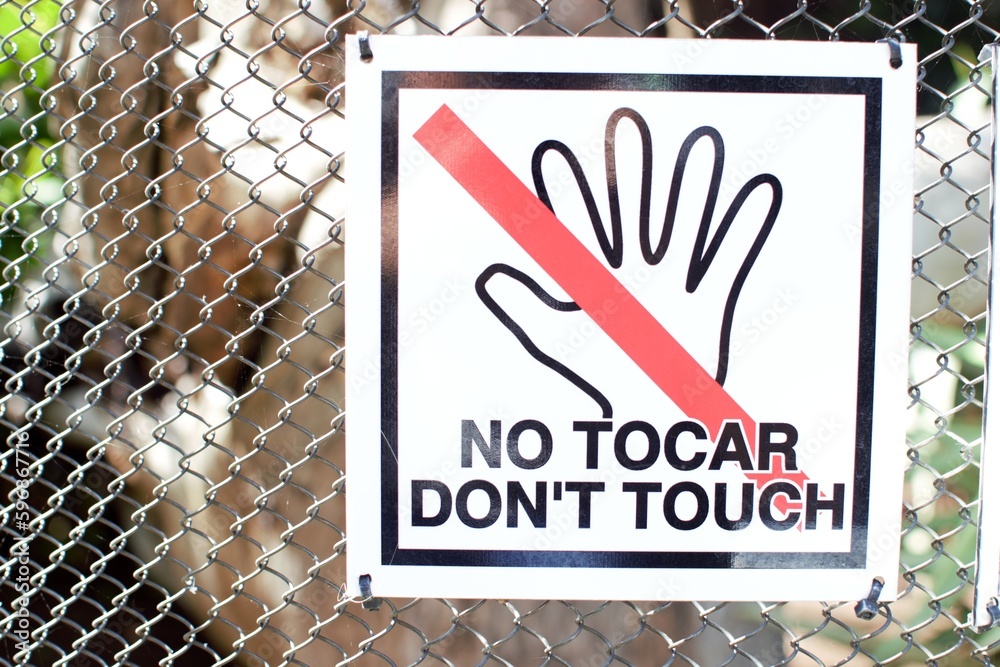 A sign with a crossed hand hanging on a metal grid informing about the ...