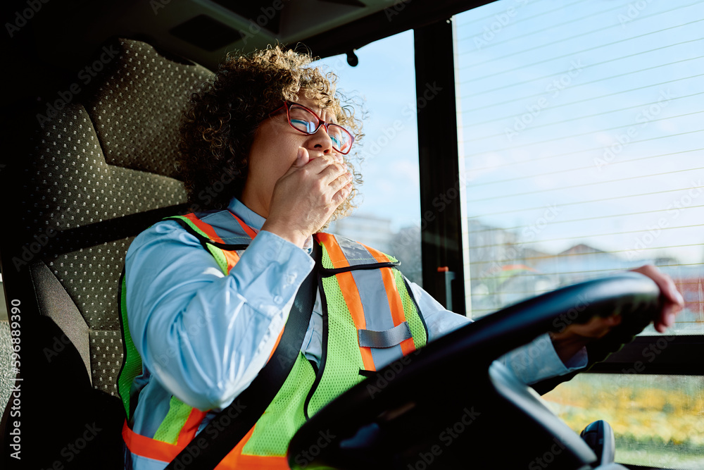 Tired female driver yawning while driving bus. Stock Photo | Adobe Stock