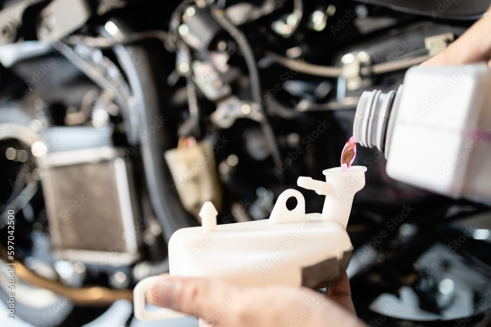 Motorcycle mechanic filling coolant in expansion tank after cleaning ...