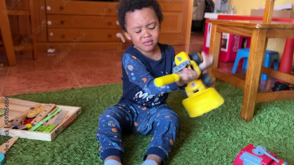 Scene of a 3-year-old cute black child playing at home to fix his toy ...