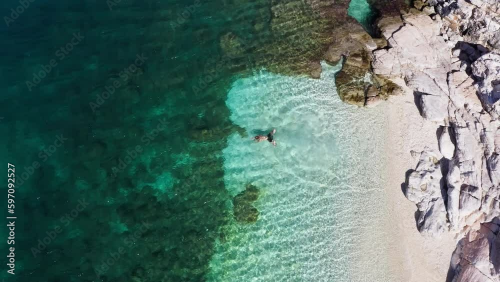 Top view 4K drone video of man dressed black swimming trunks entering ...