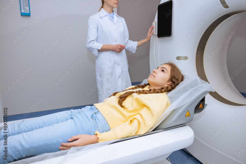 Little girl lying on table of mri scan machine female radiographer ...