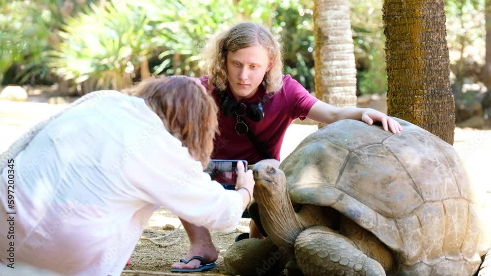 Mother tourist making a photo of son using cell phone with Aldabra ...