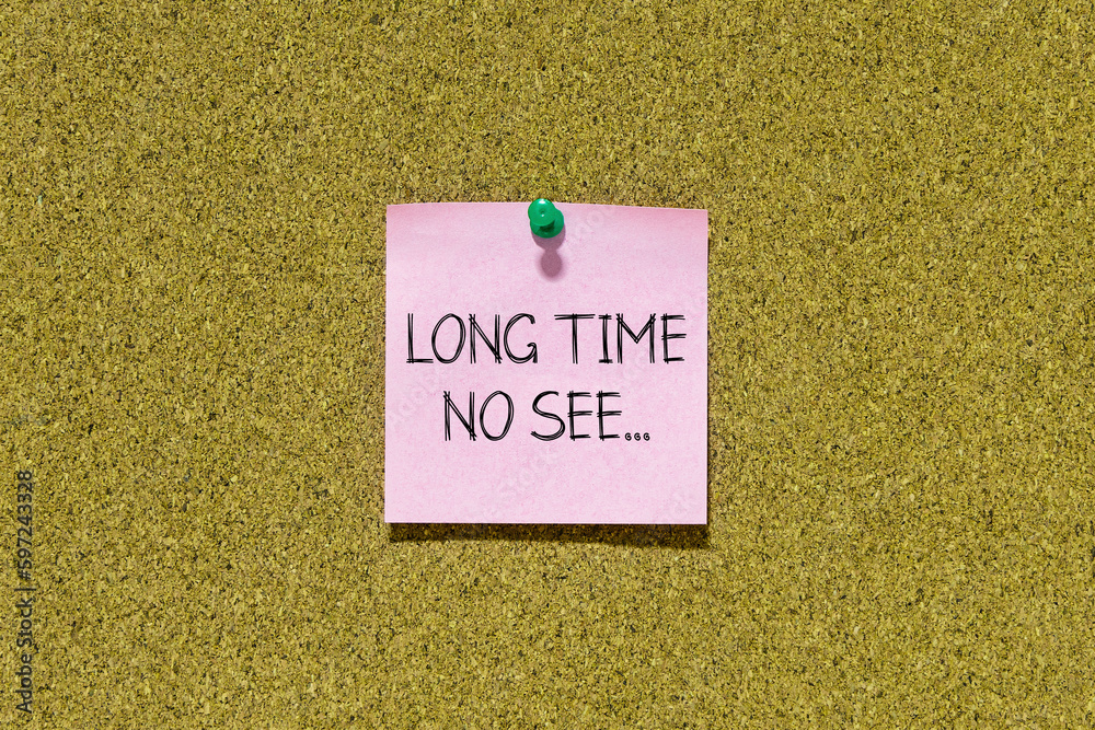 Long time no see text on pink post-it paper pinned on bulletin cork ...