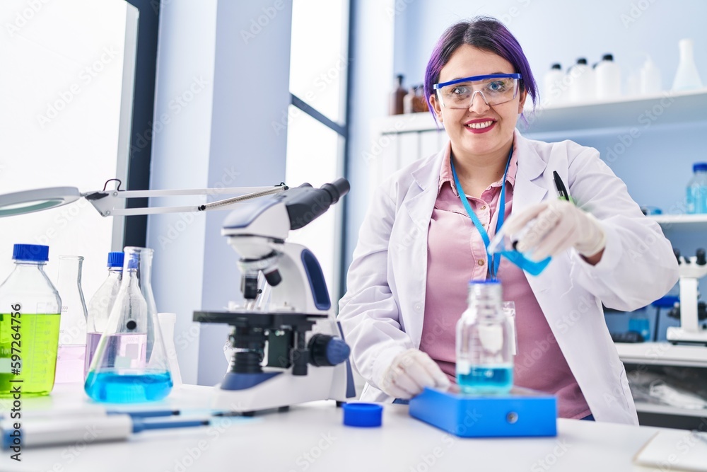 Young beautiful plus size woman scientist pouring liquid on test tube ...