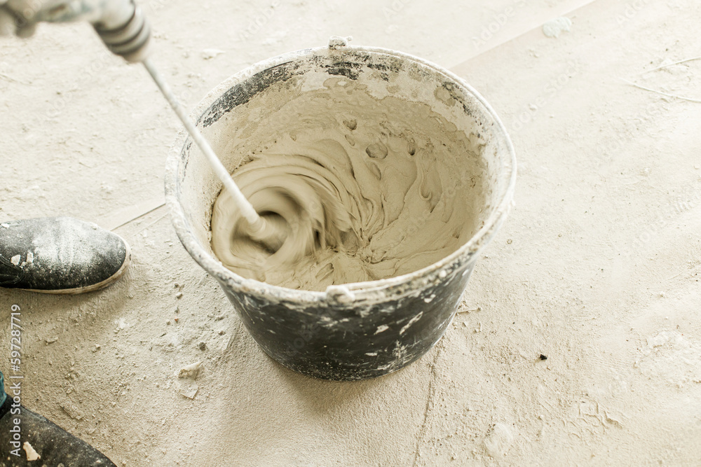 Worker mixing gypsum plaster with water for plastering walls ...