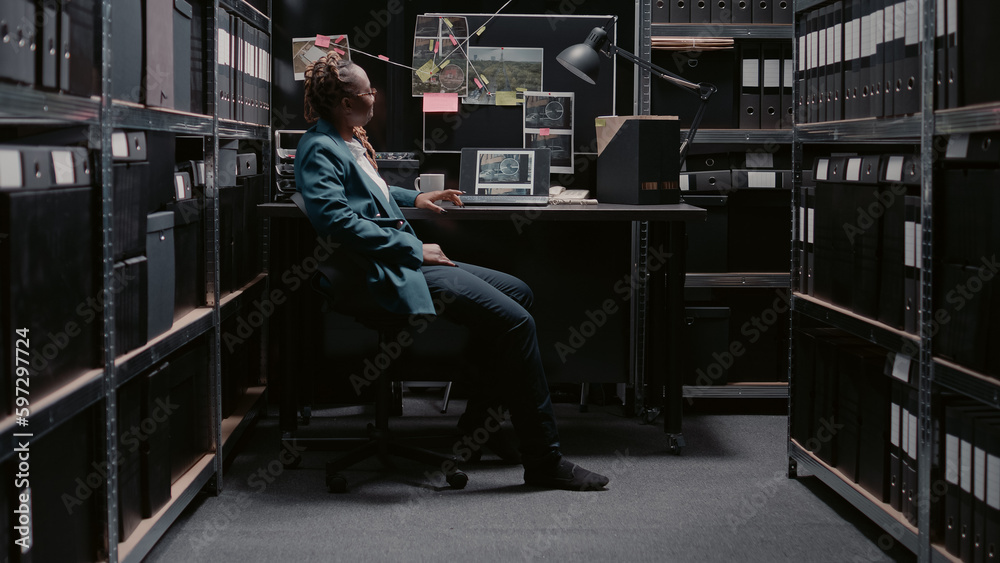 African american woman examining evidence map to find suspect, using ...