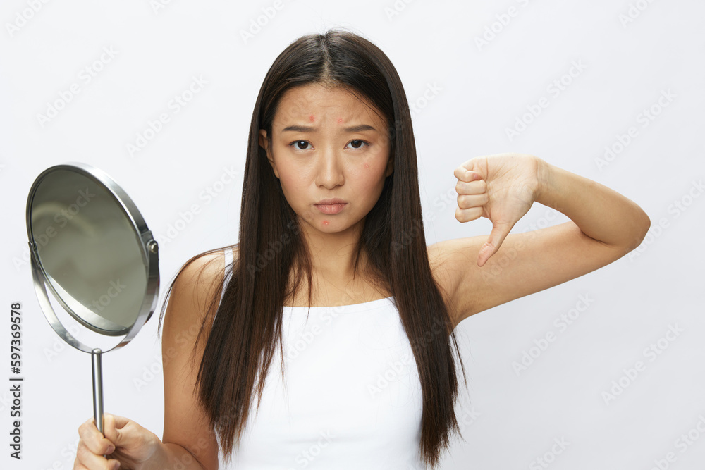 Asian woman with mirror in hand facial skin problems, acne and ...