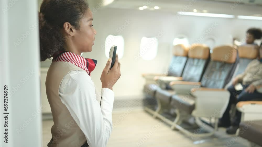 Flight attendant speaking through a loudspeaker to welcome passengers ...