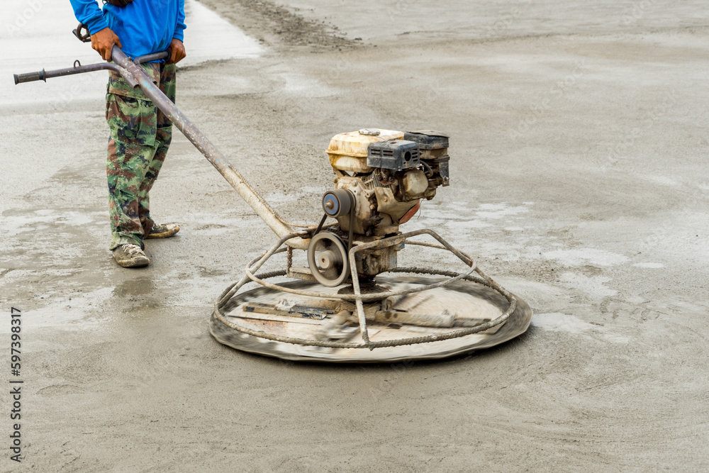 Construction worker is trowelling and finishing wet concrete with ...
