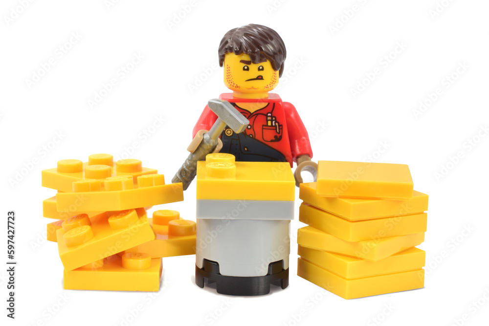 Lego minifigure of worker in uniform holds a hammer in a hand and makes ...