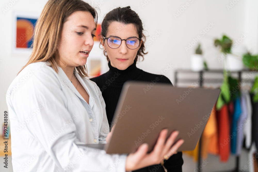 Positive young female team in casual clothes and checking laptop while ...