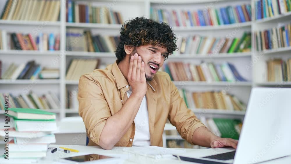 Sad student suffering from toothache working on laptop while sitting in ...