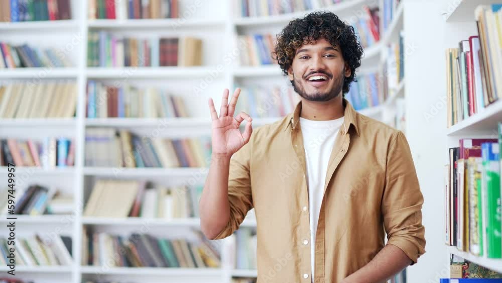 Portrait of smiling university student doing ok sign with fingers ...
