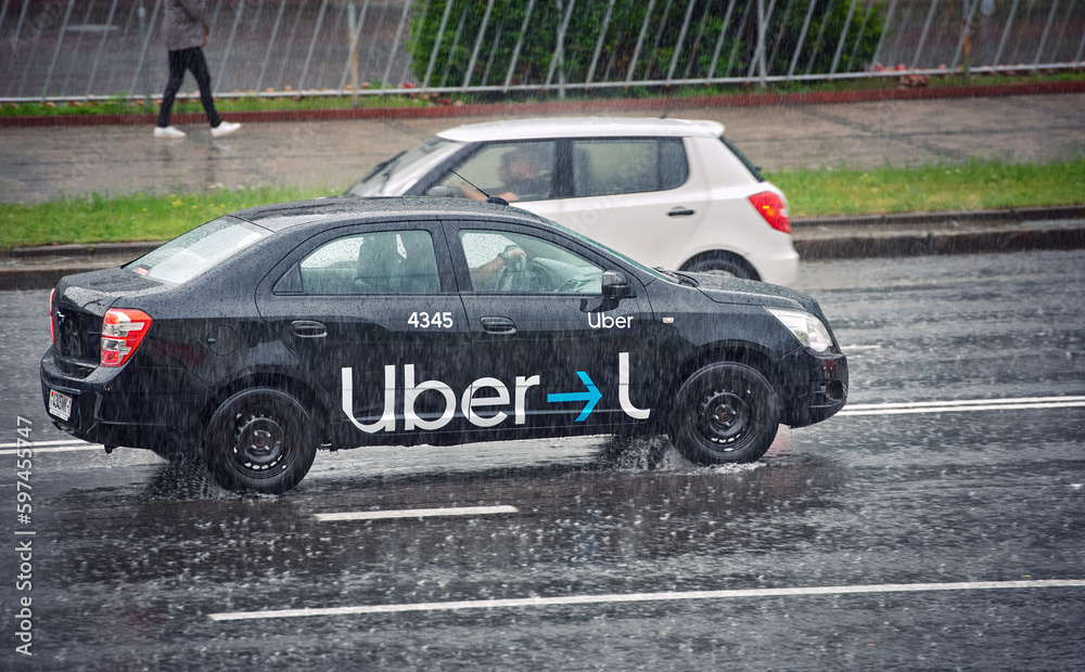 Minsk, Belarus. Jul 2022. Uber Taxi car driving through puddle at heavy ...