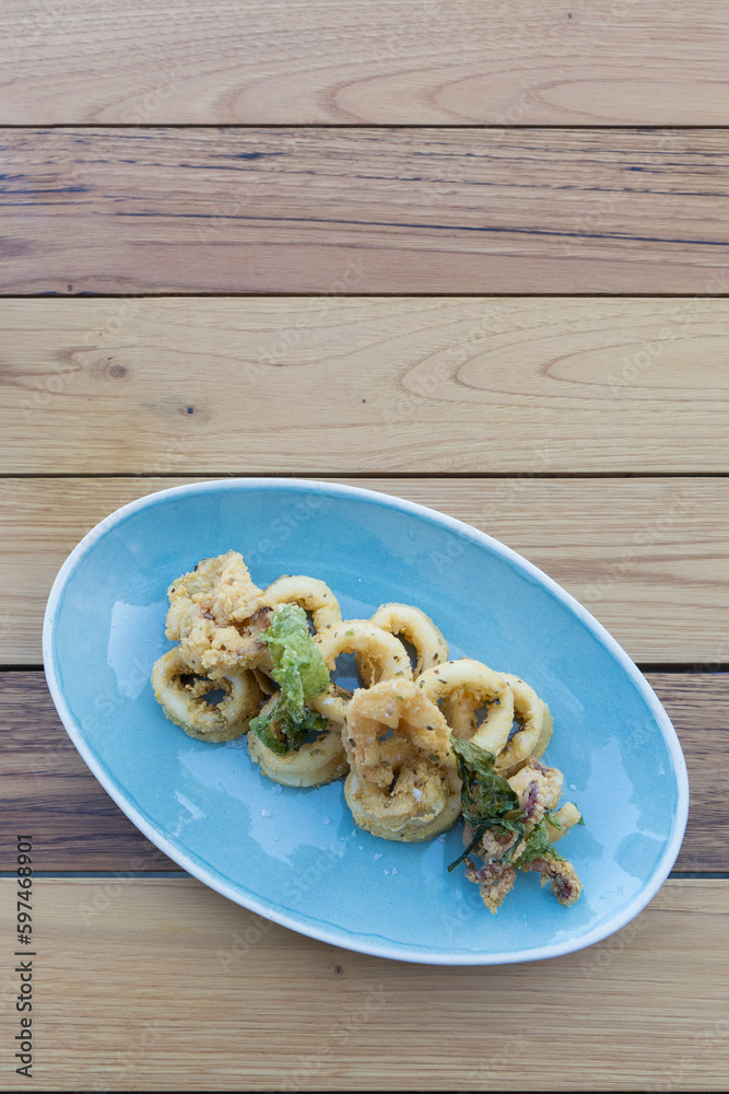 Isolated blue plate of breaded calamari rings, typically known by ...