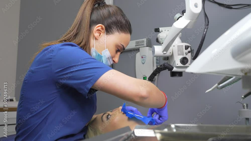 Dentist's hands in gloves with dental punch and cofferdam scarf ...