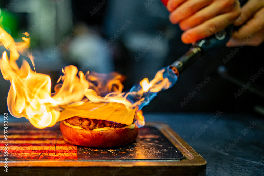 preparing a gourmet cheeseburger on restaurant kitchen with fire Stock ...
