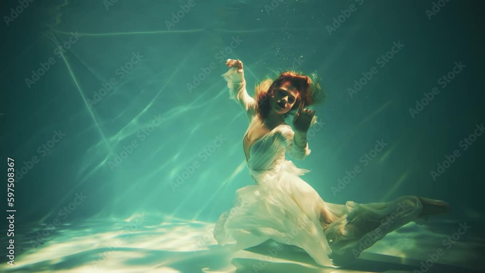 Fantasy woman drowns under dark blue water falls to bottom sea. Wet ...