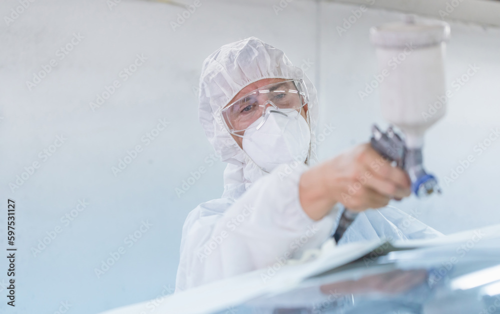 Mechanic painting car in chamber. Worker using spray gun and airbrush ...