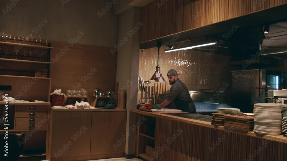 Full shot of Caucasian male chef in black uniform and apron cleaning ...