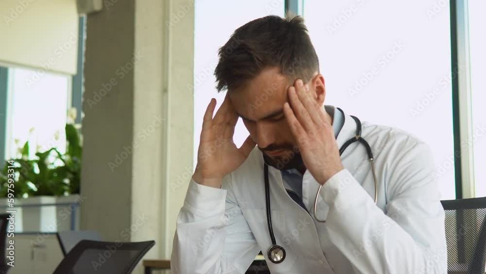Stressed frustrated doctor wearing white uniform with headache sitting ...