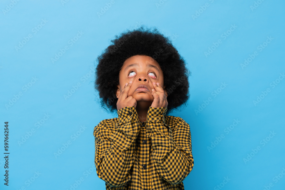 Afro African boy doing funny ghost face in light blue isolated ...