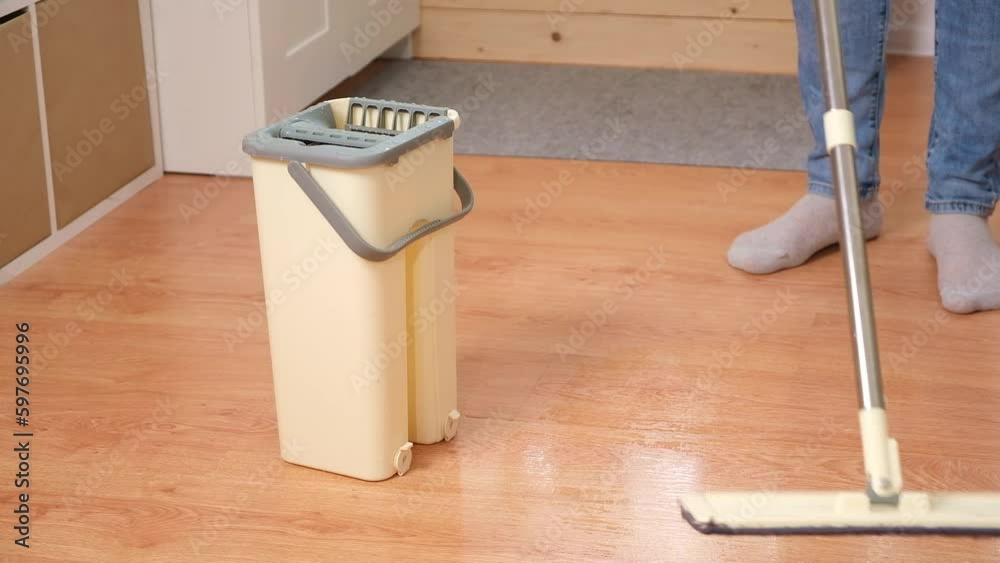 A man squeezes a mop into a bucket and washes the floor. Husband ...