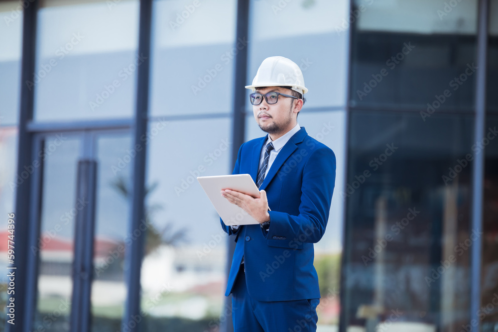 Handsome engineer wearing suit and hard hat or white helmet on building ...