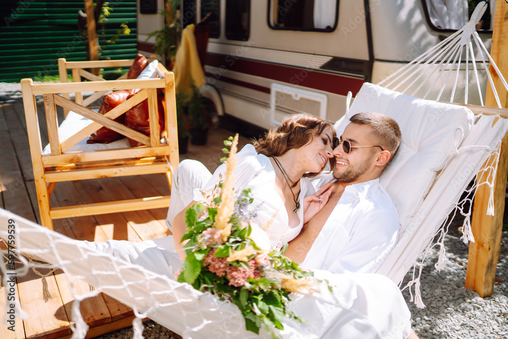 Wedding couple are resting in a trailer. Newlyweds tenderly embrace ...