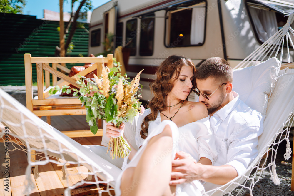 Wedding couple are resting in a trailer. Newlyweds tenderly embrace ...