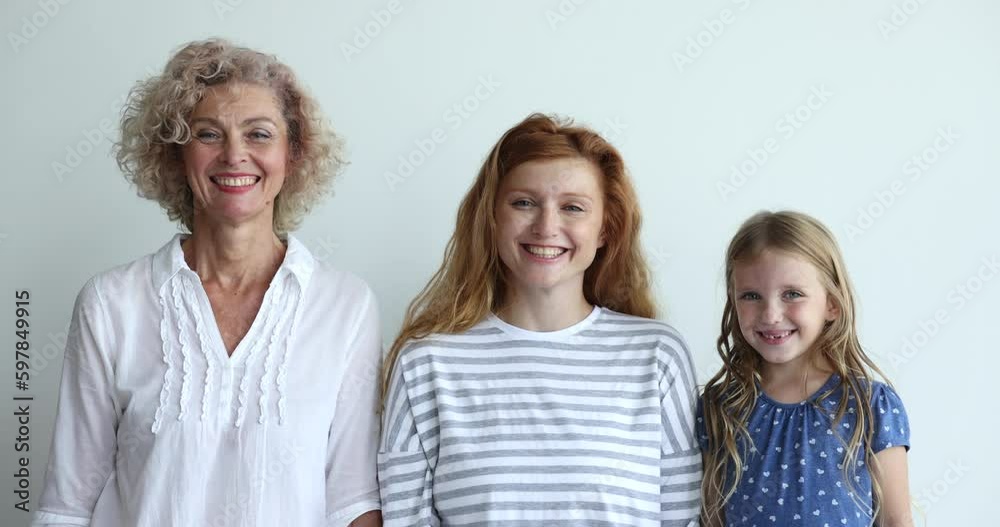 Pretty girls and women of three family generations posing at white wall ...