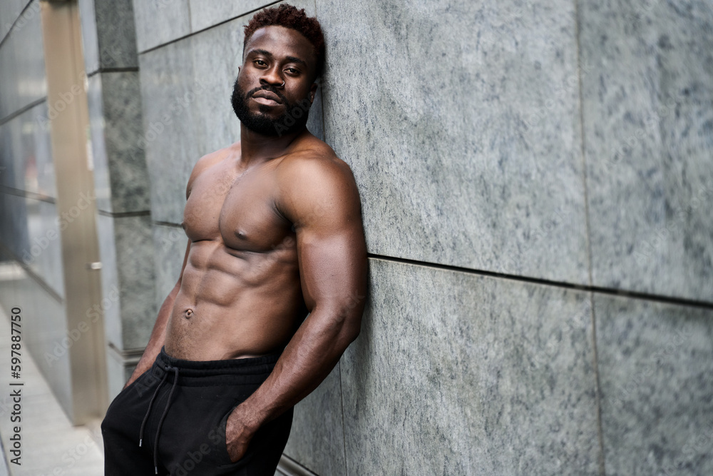 Fit strong sexy shirtless young African man standing at urban wall ...