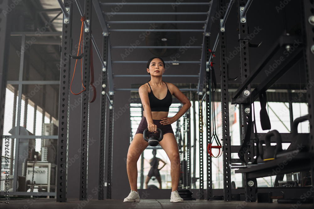 Strong asian woman doing exercise with kettlebell at crossfit gym ...