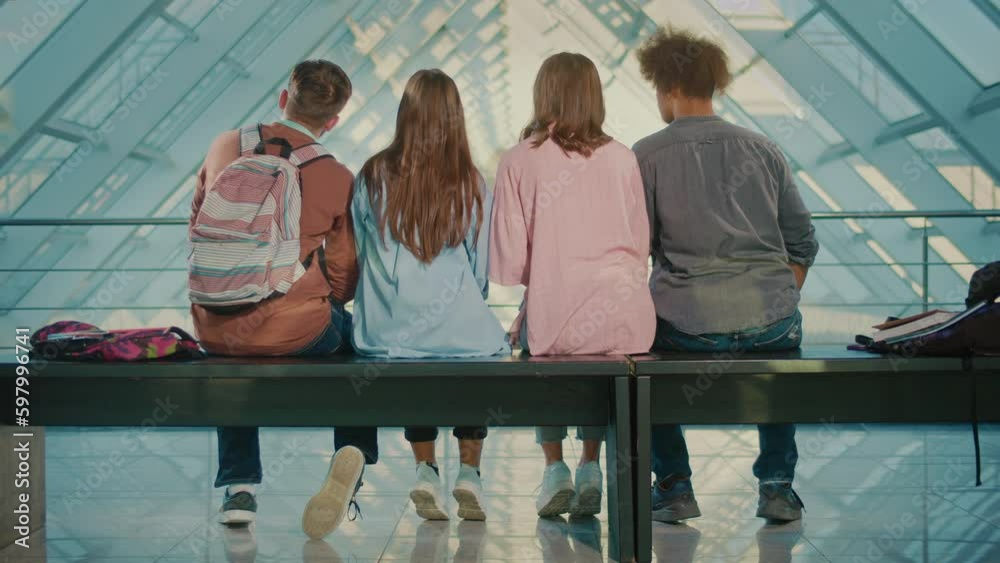 Back view of Students Sitting on Bench in the University HallWay During ...