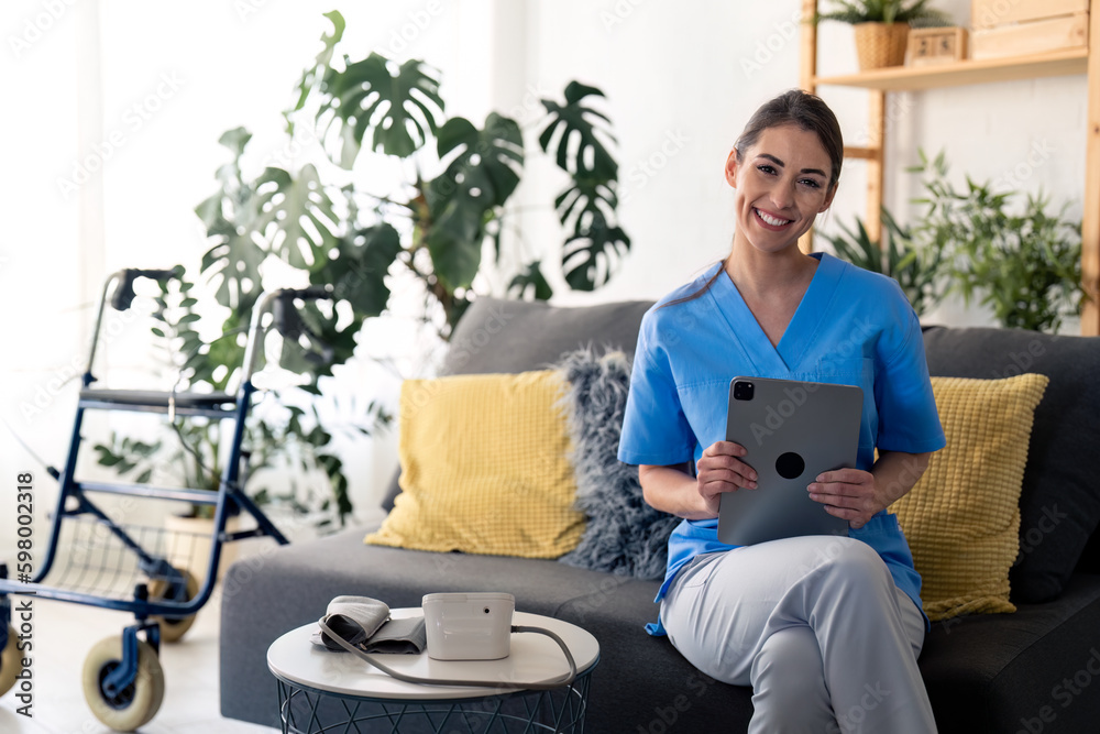Confident smiling young nurse looking at camera holding digital tablet ...