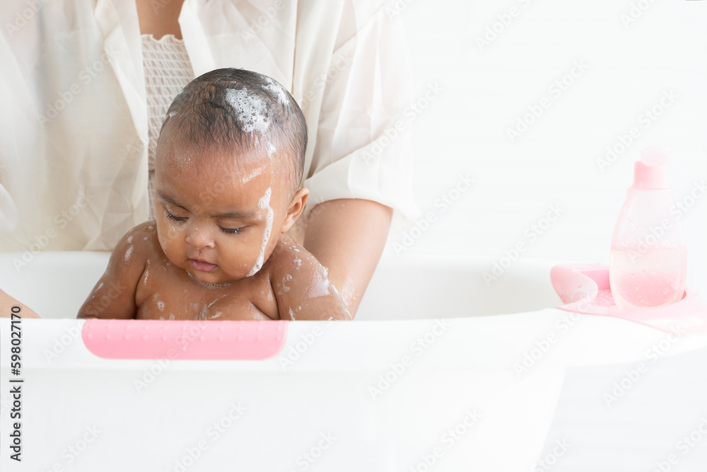 Foto de Cute African newborn baby bathing in bathtub with soap bubbles ...
