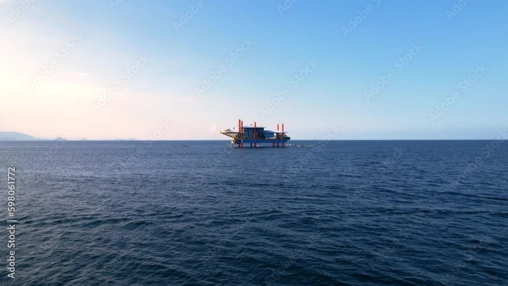 An offshore oil rig in the middle of the ocean, towering over the ...