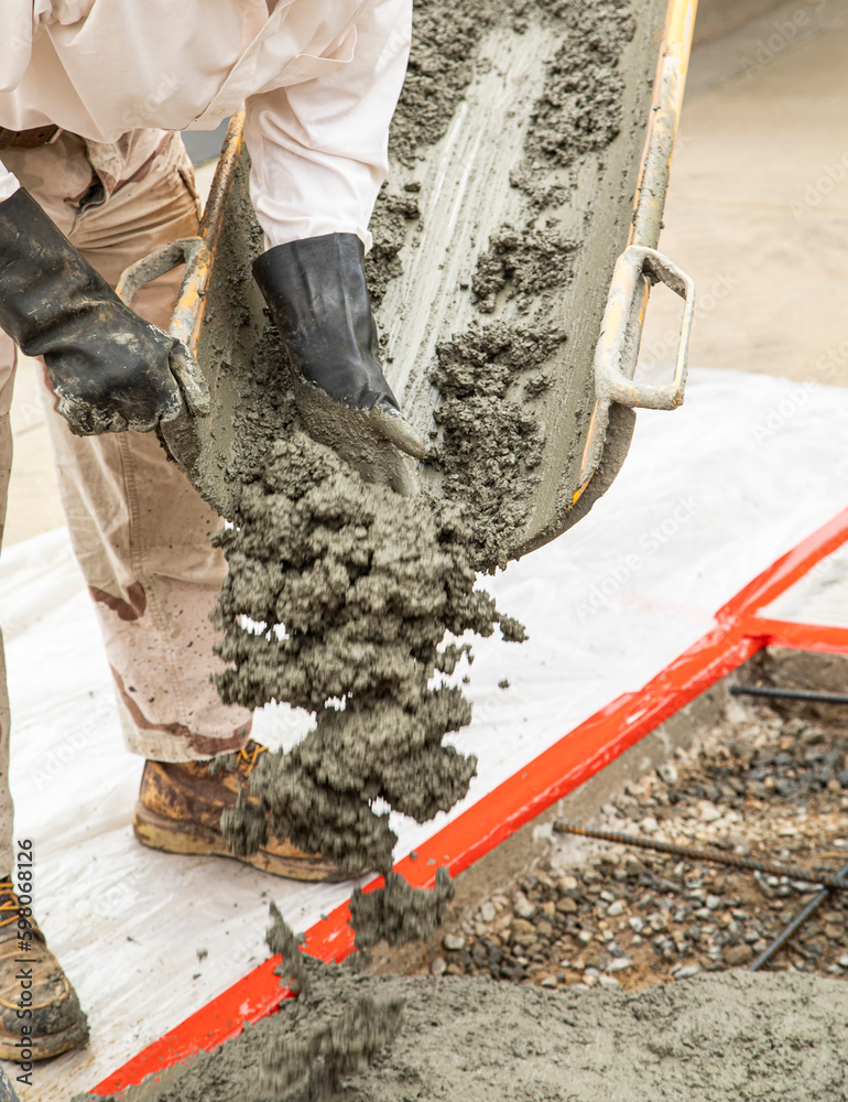 Wet cement off loaded by construction workers from a cement truck chute ...