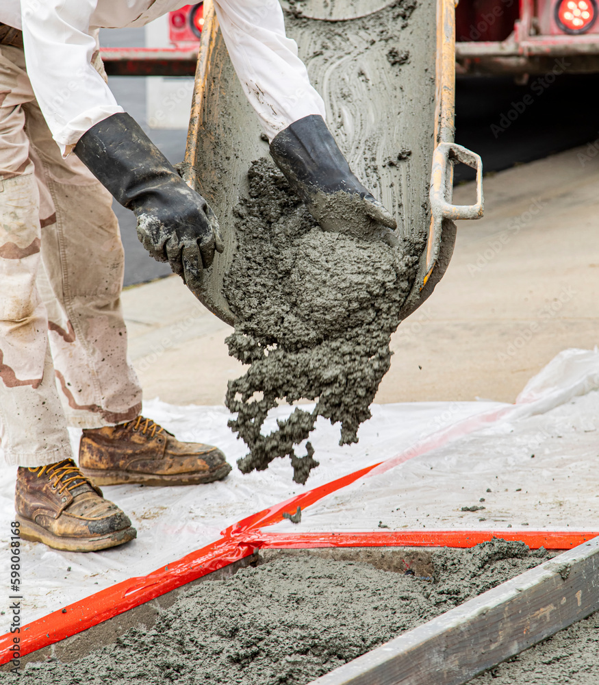 Wet cement off loaded by construction workers from a cement truck chute ...