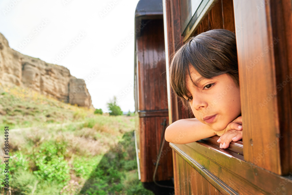 boy leaning out the window of a vintage train during a canyon ride ...