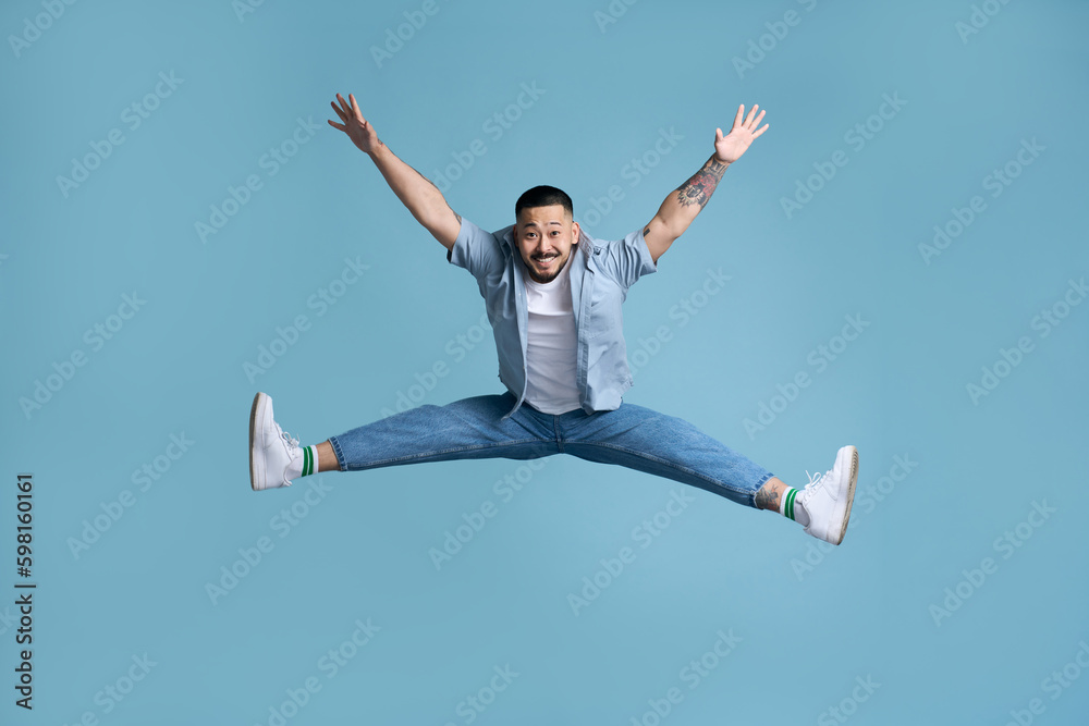 Full length portrait of positive inspired asian man jumping in air ...