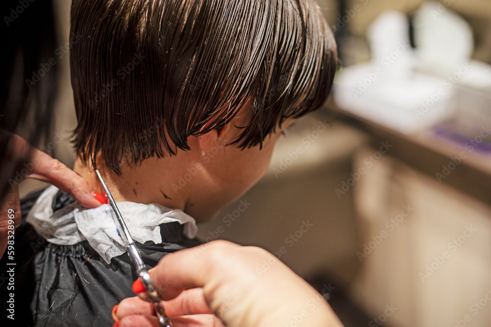 barbershop cuts the tips of wet clean hair on the back of the head of a ...