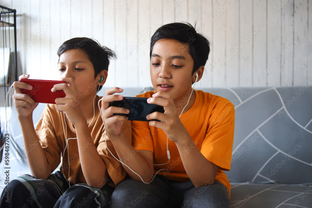 Two kids playing games with gadgets on couch. Modern communication and ...