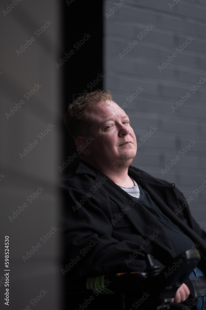 A disabled wheelchair user poses in a doorway between two black walls ...
