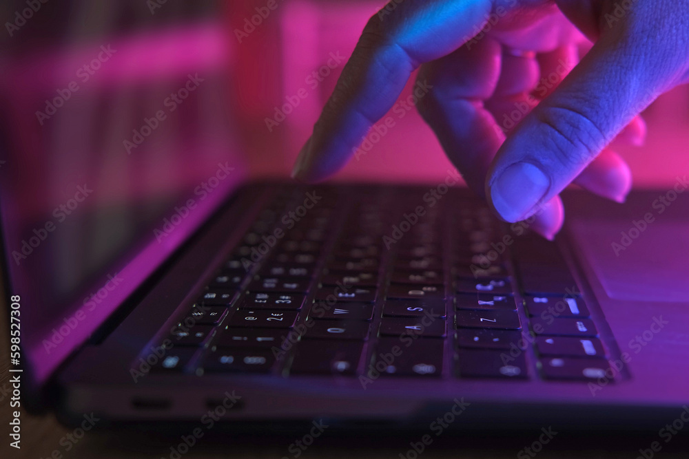 Person typing at laptop computer at night. Female uses keyboard, shakes ...