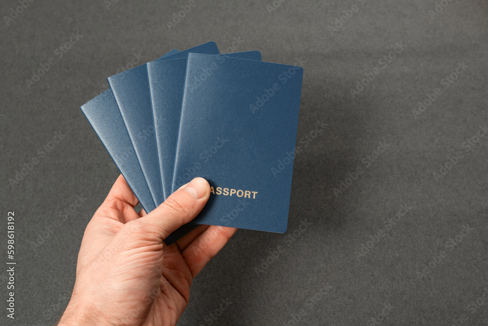 Four blue passports with blank covers in mans hand on black background ...