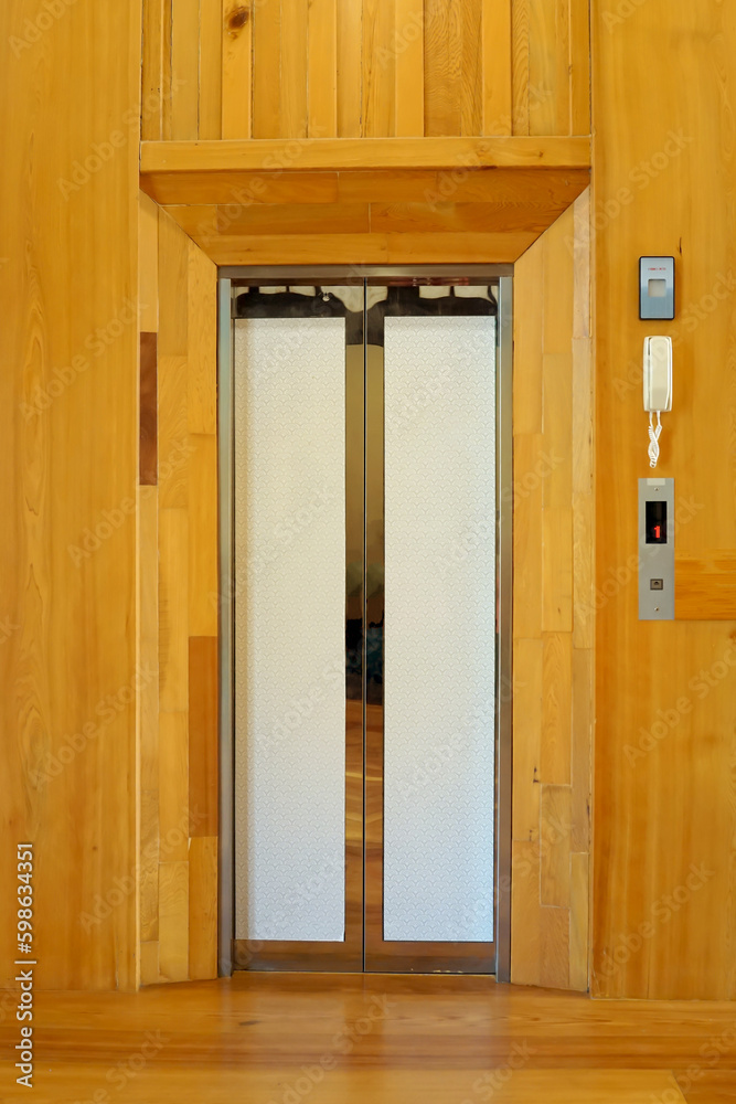 Japanese-style elevator with wooden walls white sticker door. It looks ...